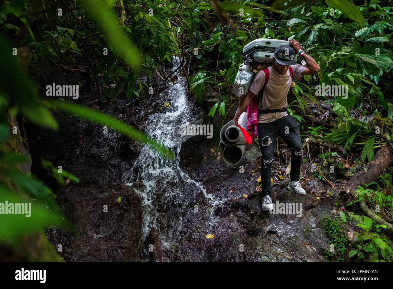 A Venezuelan migrant climbs down a rocky trail alongside a waterfall in ...