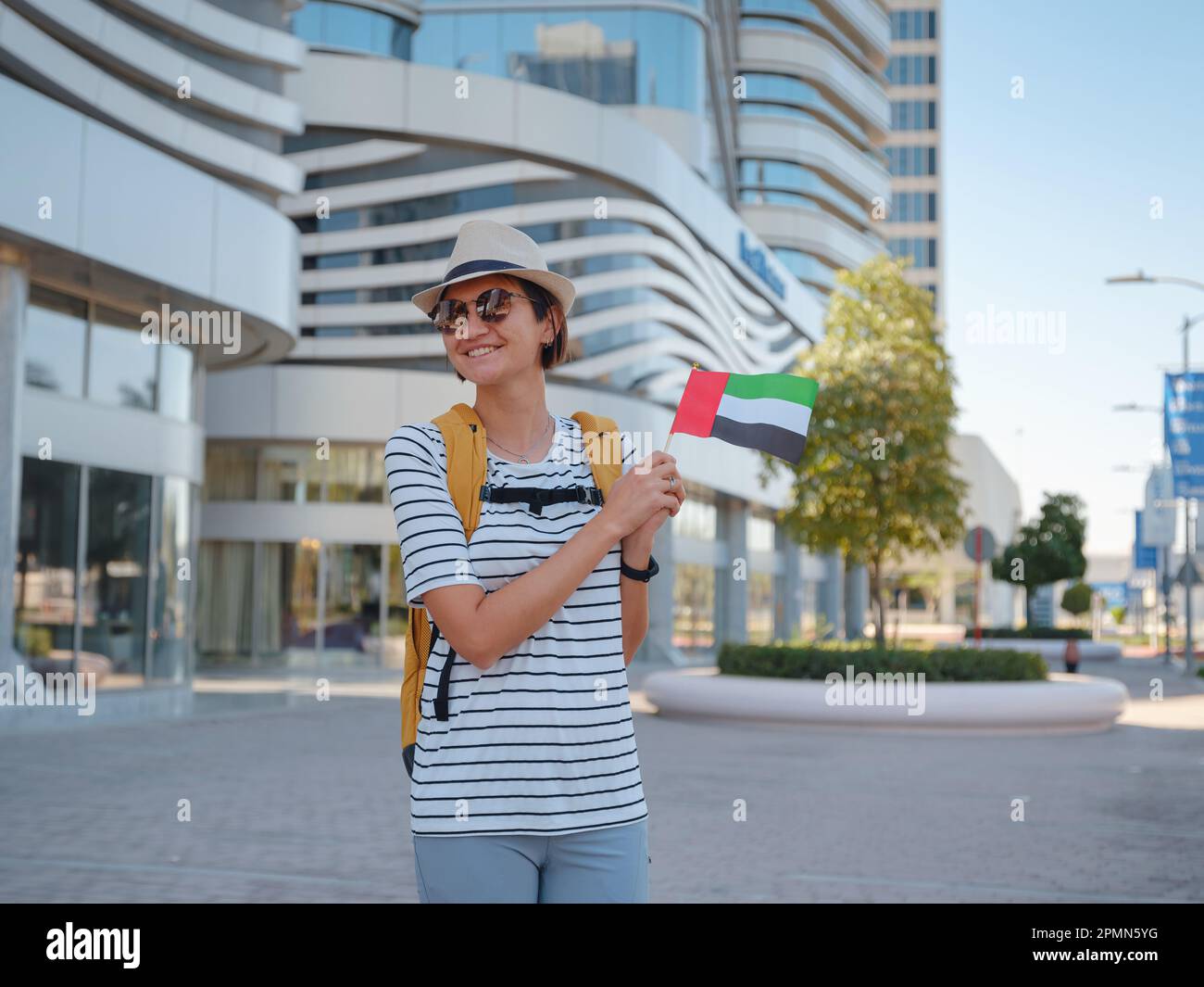 Happy young asian female traveler with backpack and hat with UAE flag ...