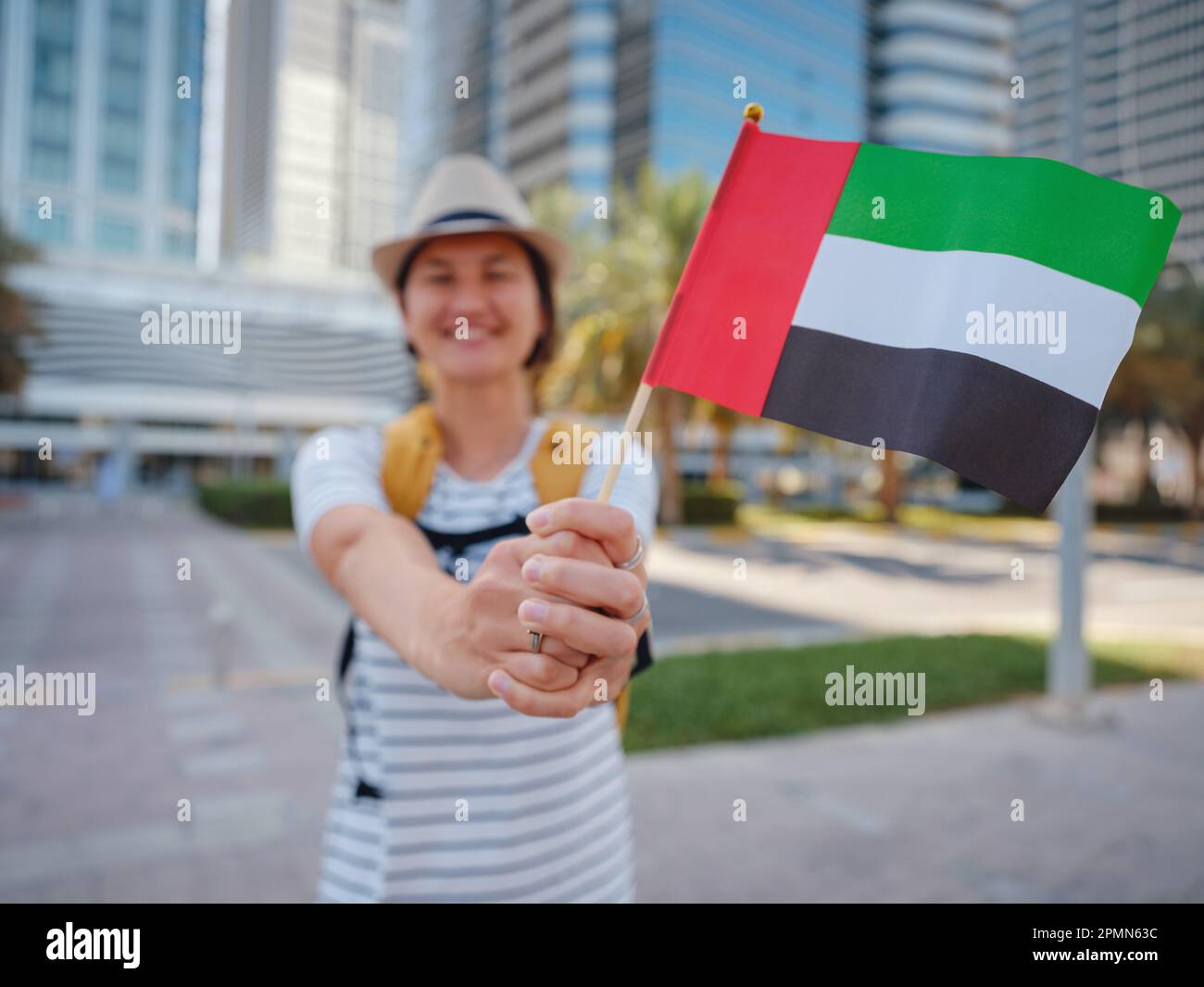 Happy young asian female traveler with backpack and hat with UAE flag ...