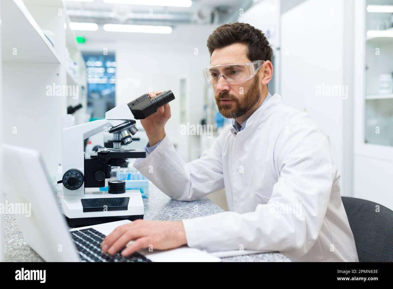 Serious and thoughtful scientist working in laboratory with microscope ...