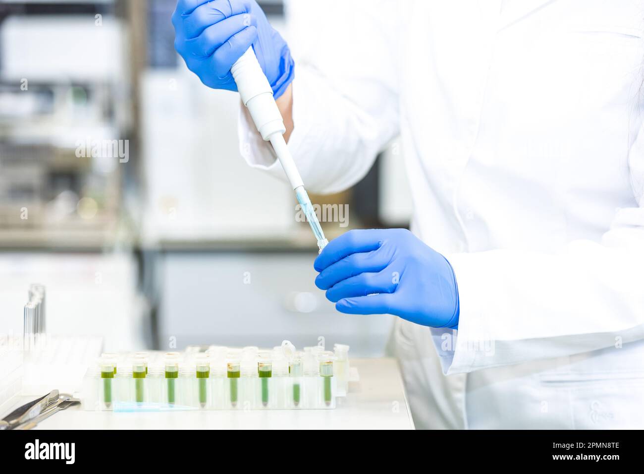 Scientist with dropper dripping liquid into a test tube in scientific ...
