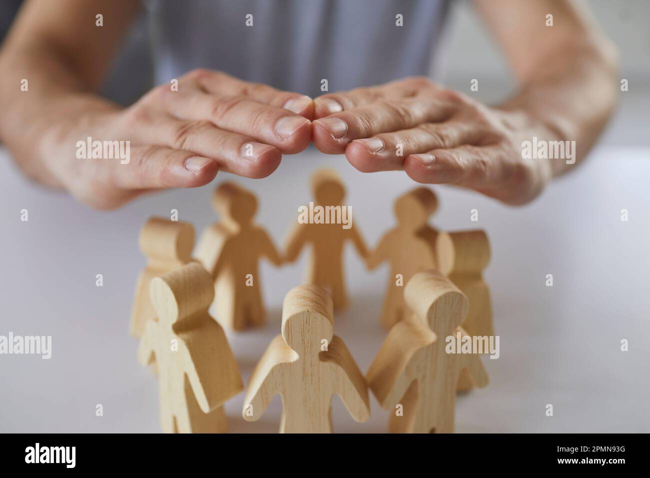 Male hands covering and protecting team of people made of wood Stock ...