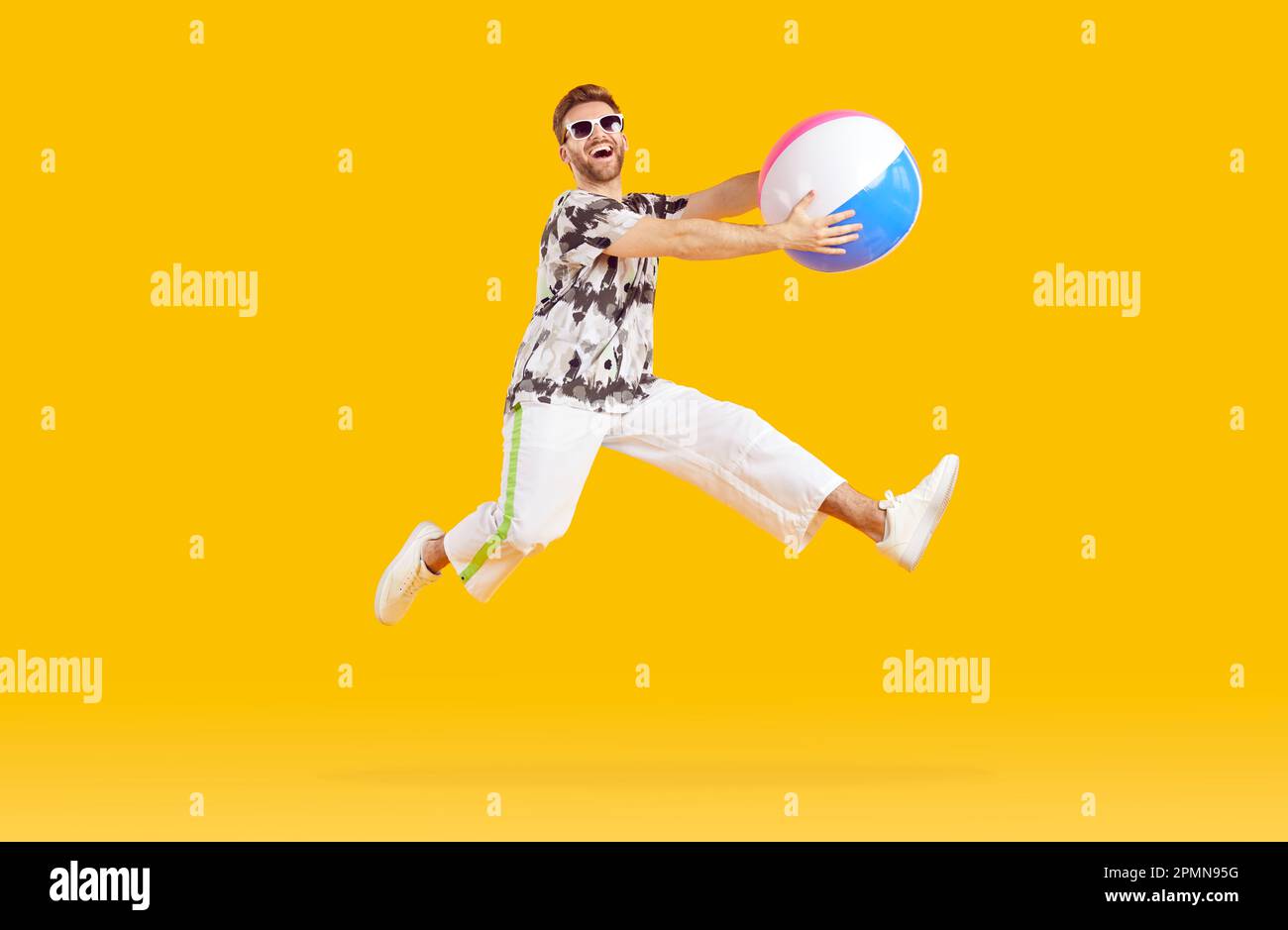 Happy man having fun during his summer holiday and playing with a ball ...