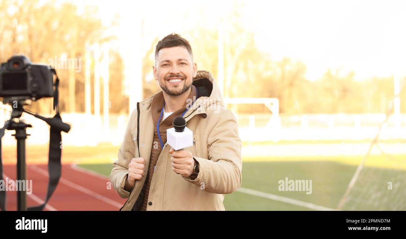 Male reporter with microphone at the stadium Stock Photo - Alamy