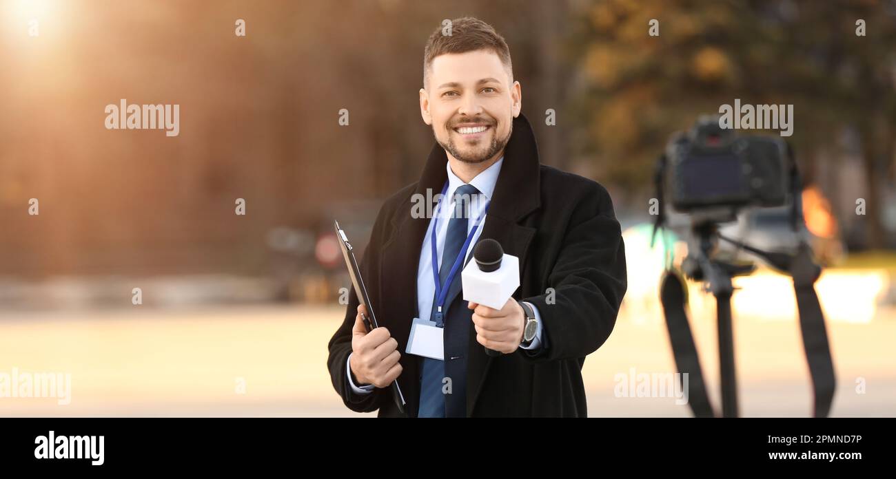 Male journalist with microphone outdoors Stock Photo - Alamy