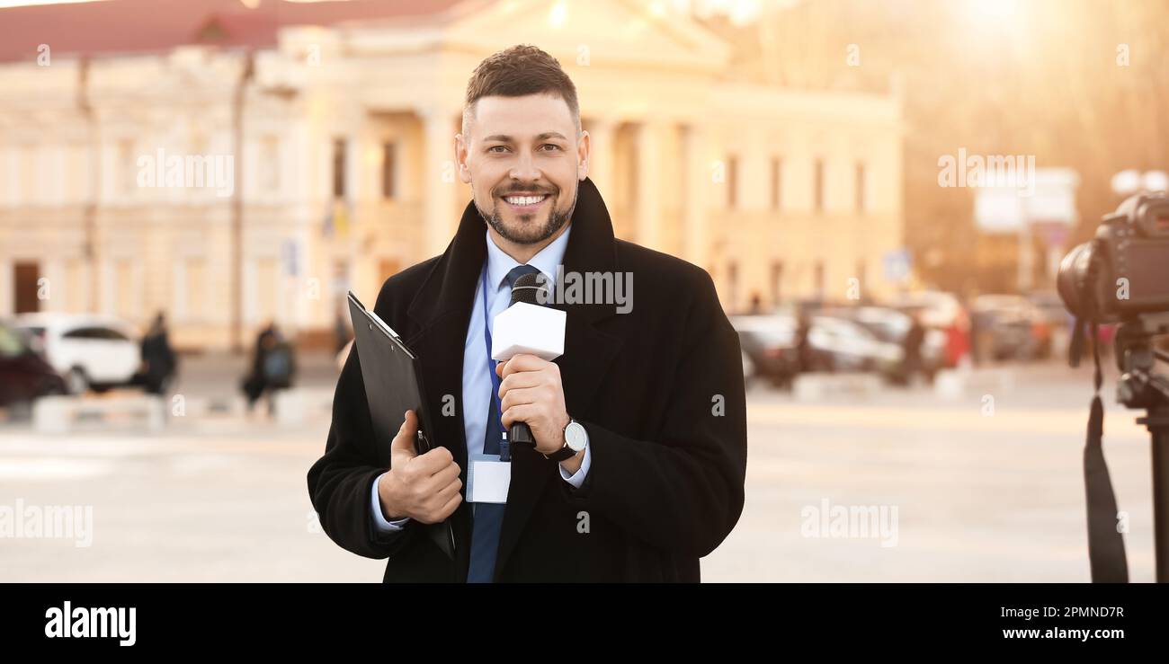 Male journalist with microphone outdoors Stock Photo - Alamy