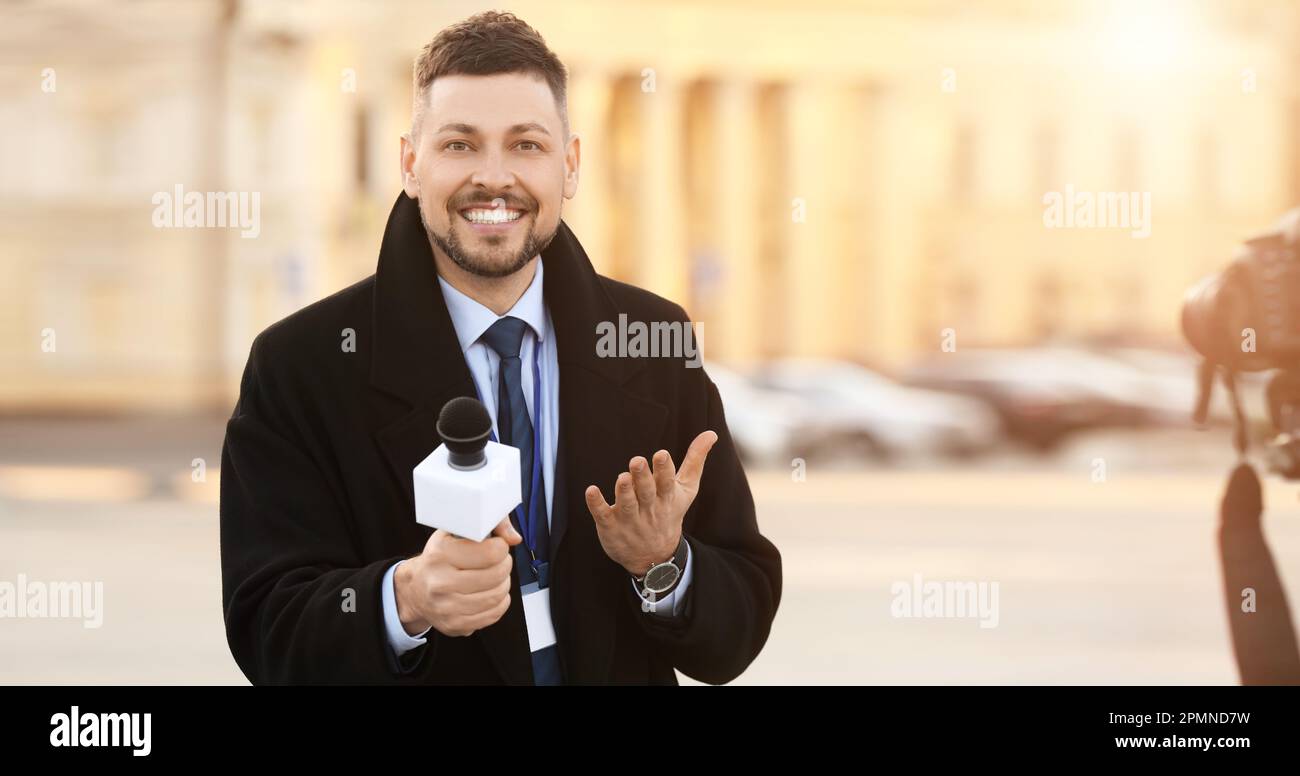 Male journalist with microphone outdoors Stock Photo - Alamy
