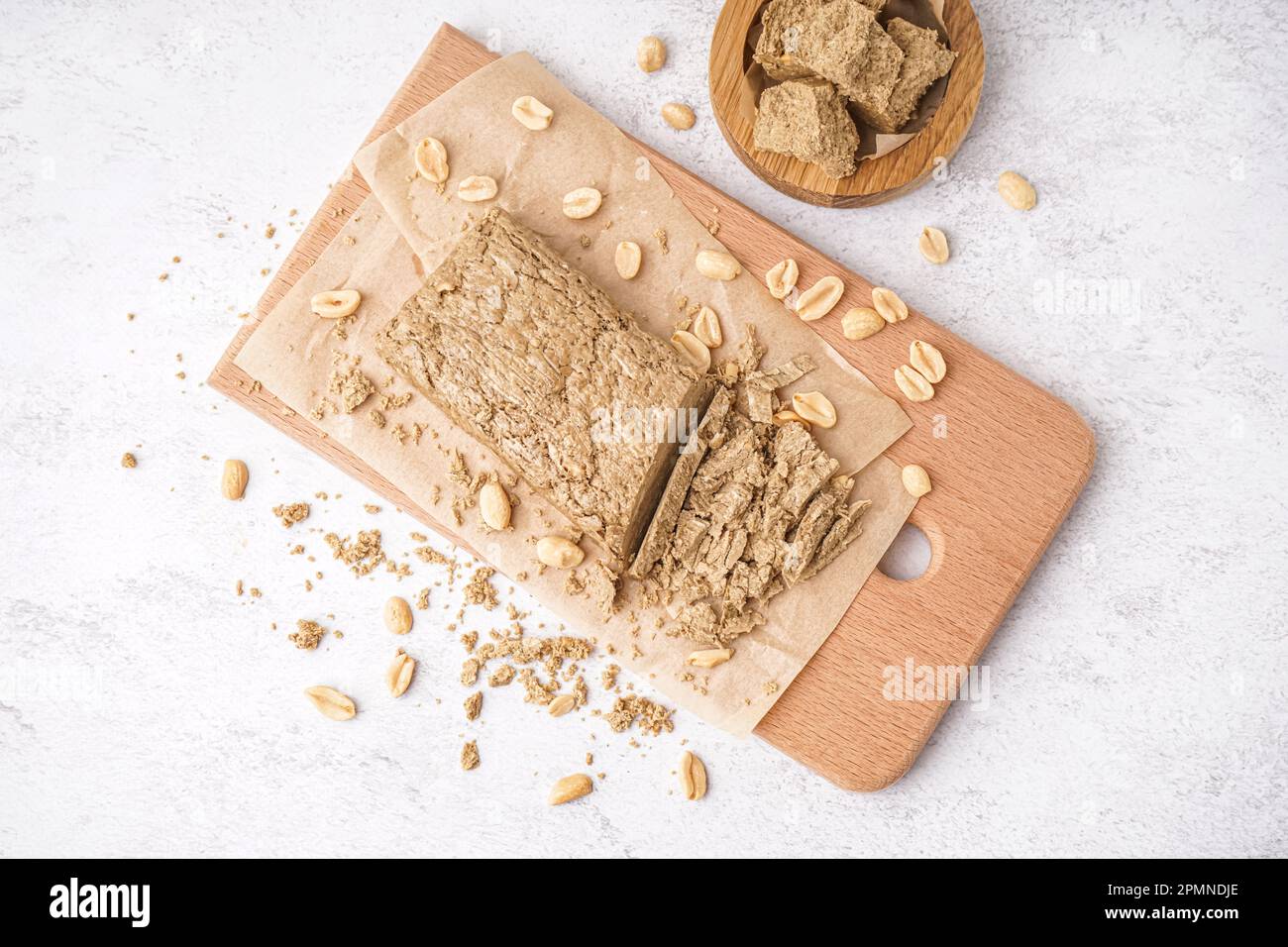 Wooden board of sweet halva with peanuts on light background Stock ...