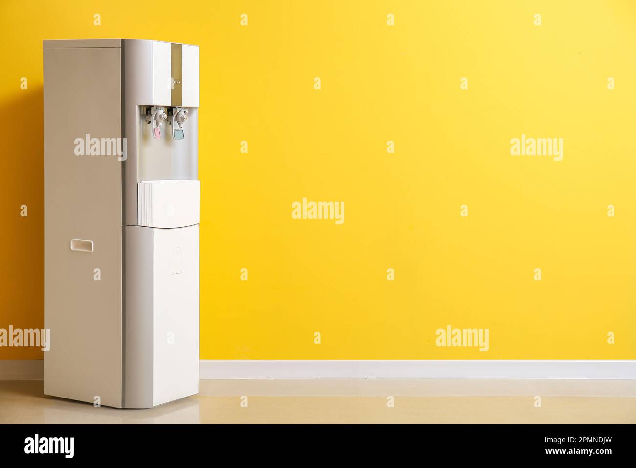 Modern water cooler near yellow wall Stock Photo - Alamy
