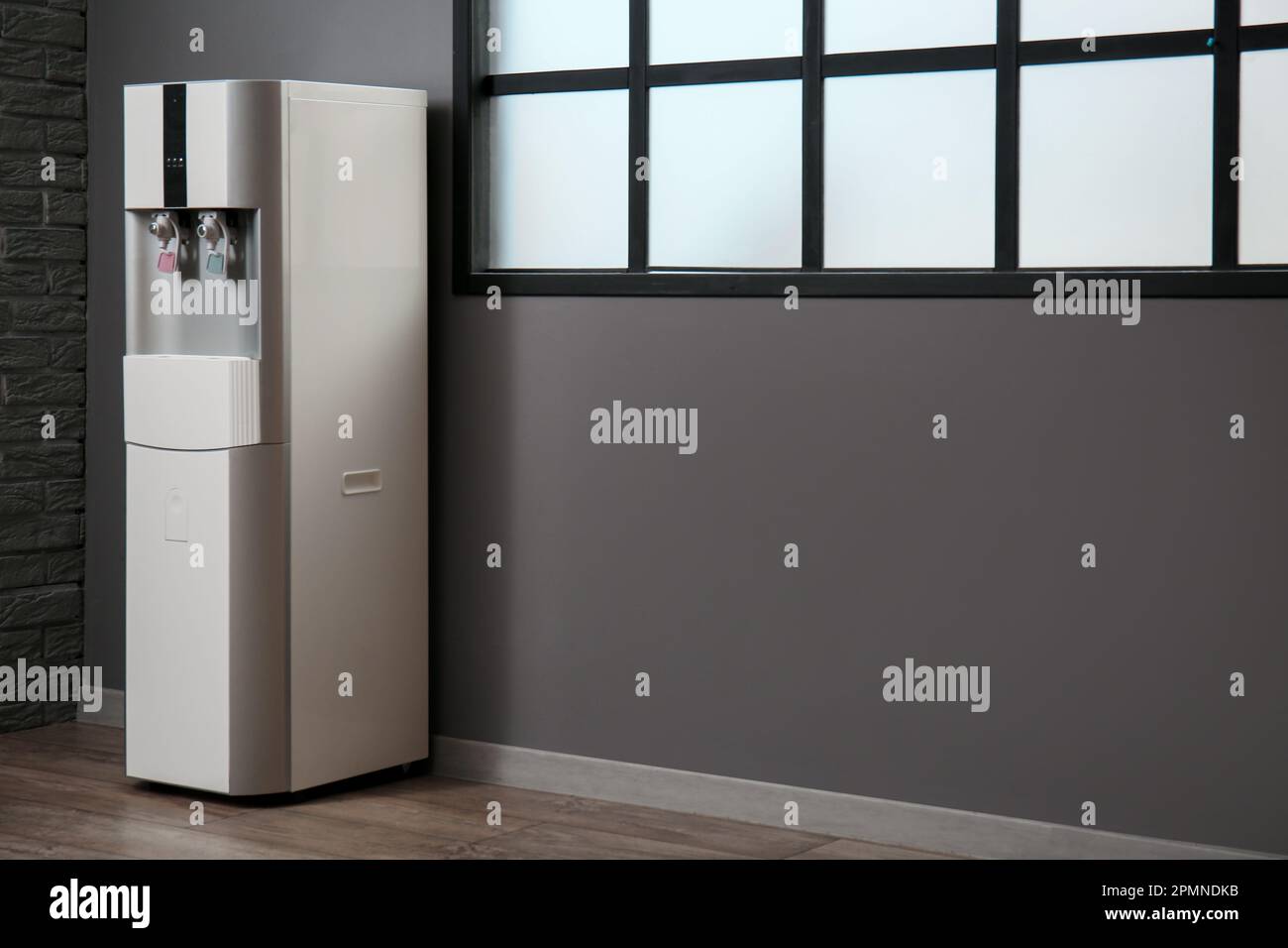 Modern water cooler near black wall and window Stock Photo - Alamy