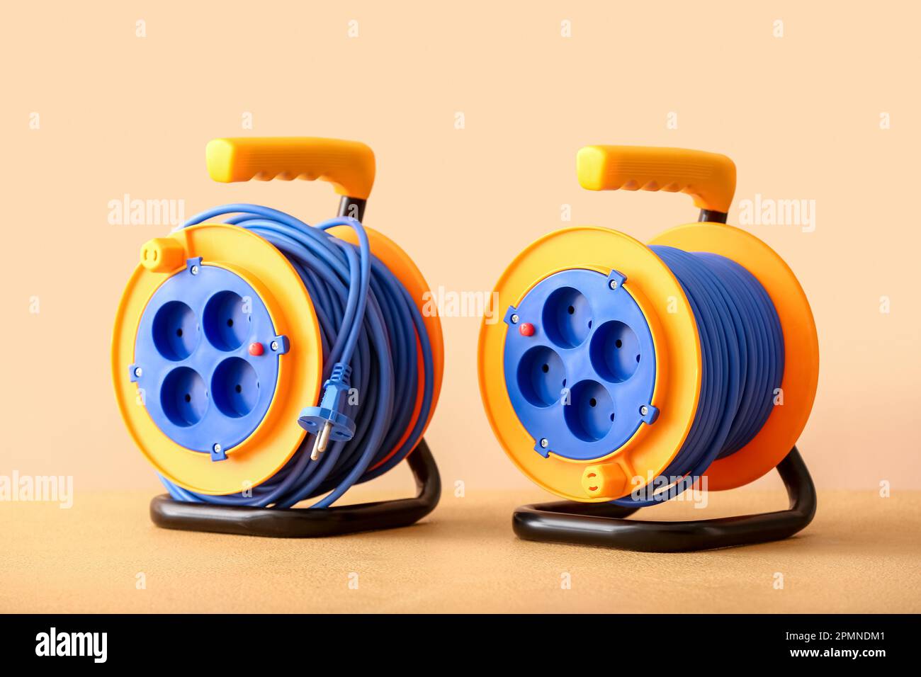 Extension electric cable reels near color wall Stock Photo - Alamy