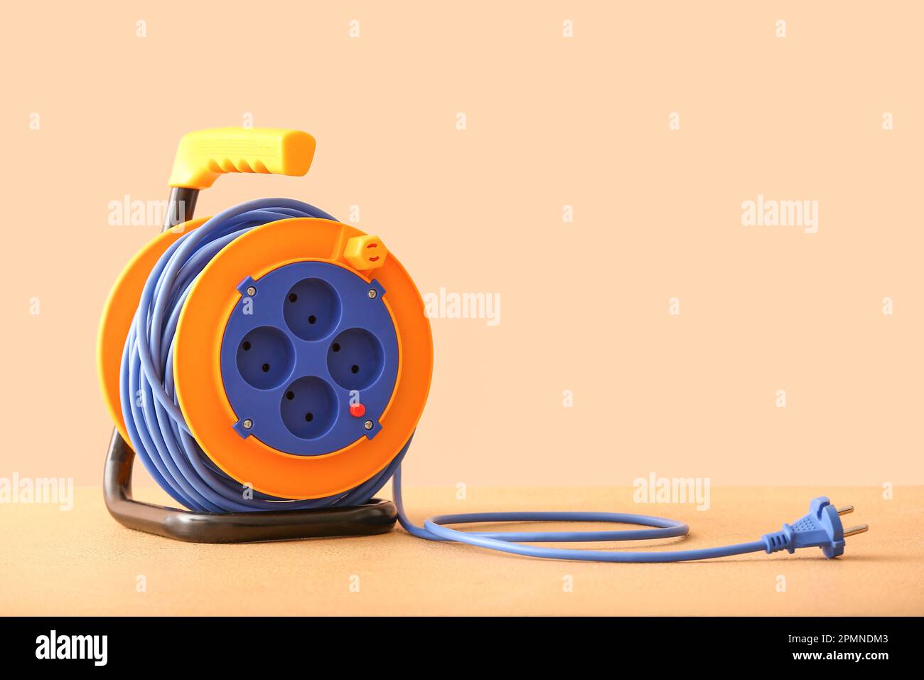 Extension electric cable reel near color wall Stock Photo - Alamy