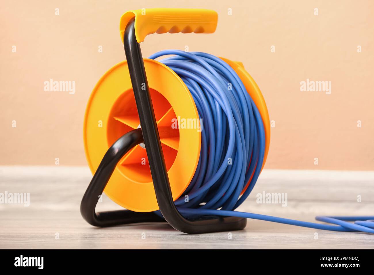 Extension electric cable reel on floor near color wall, closeup Stock ...