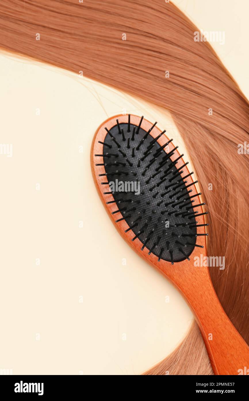 Hair strand with brush on beige background Stock Photo - Alamy