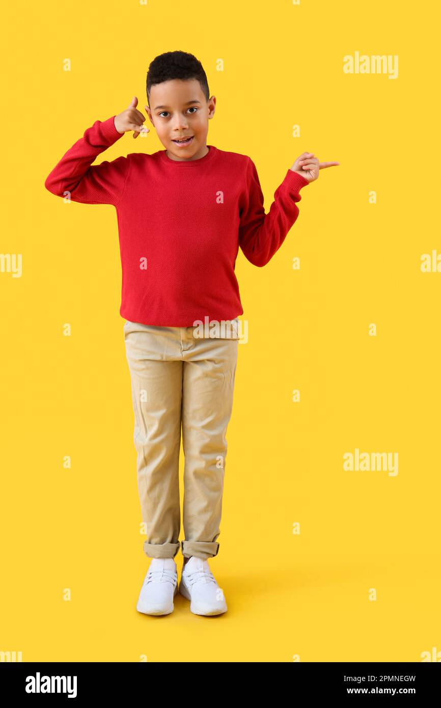 Little African-American boy showing "call me" gesture and pointing at ...