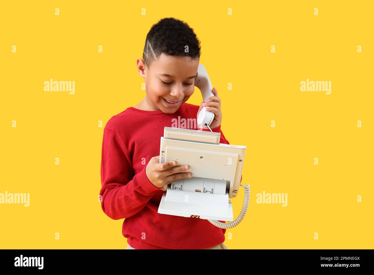 Little African-American boy talking by telephone on yellow background ...