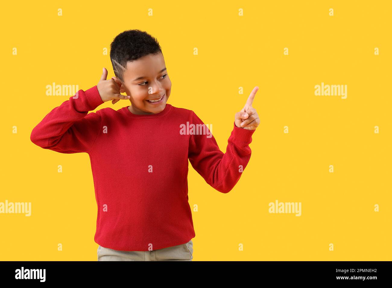 Little African-American boy showing "call me" gesture and pointing at ...