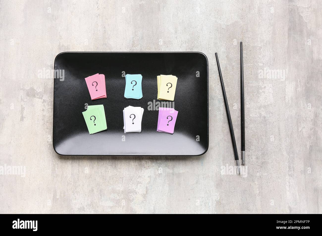 Plate with paper question marks and chopsticks on grunge background ...