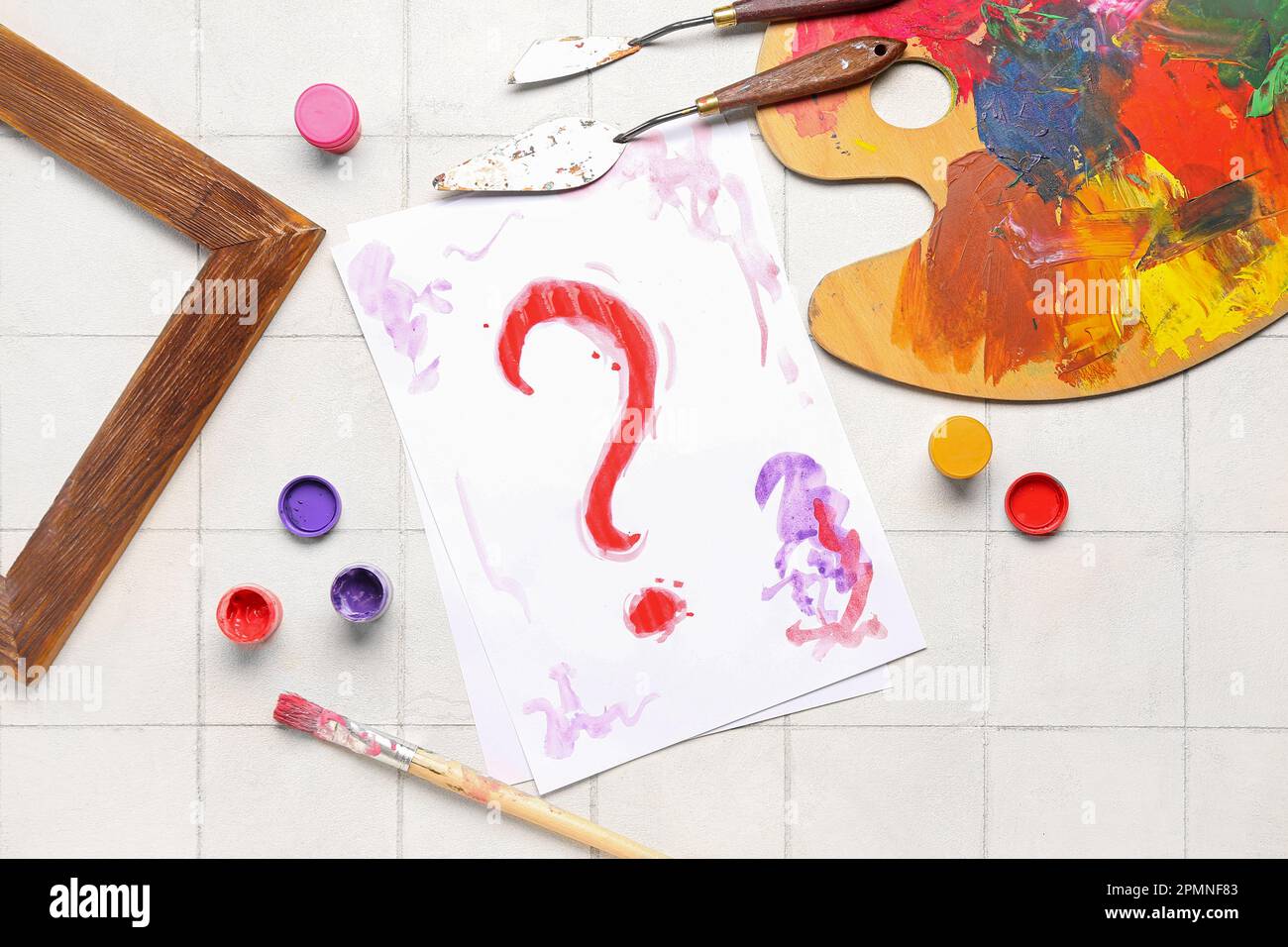 Paper with drawn question mark and paints on white tile background ...