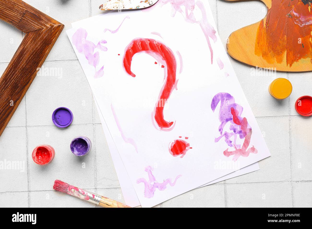 Paper with drawn question mark and paints on white tile background ...