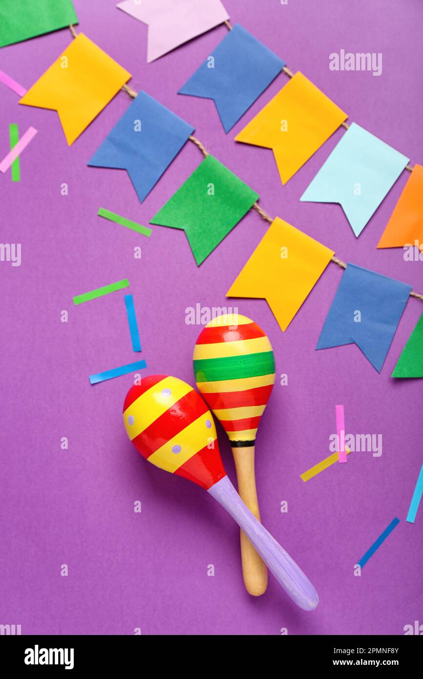 Mexican maracas with paper flags and confetti on purple background ...