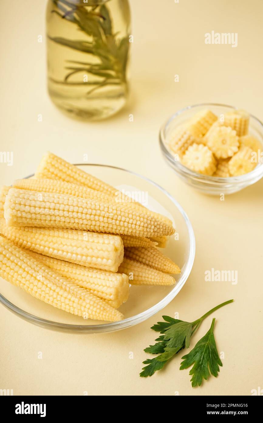 Plate with cut and whole canned baby corn cobs on yellow background ...