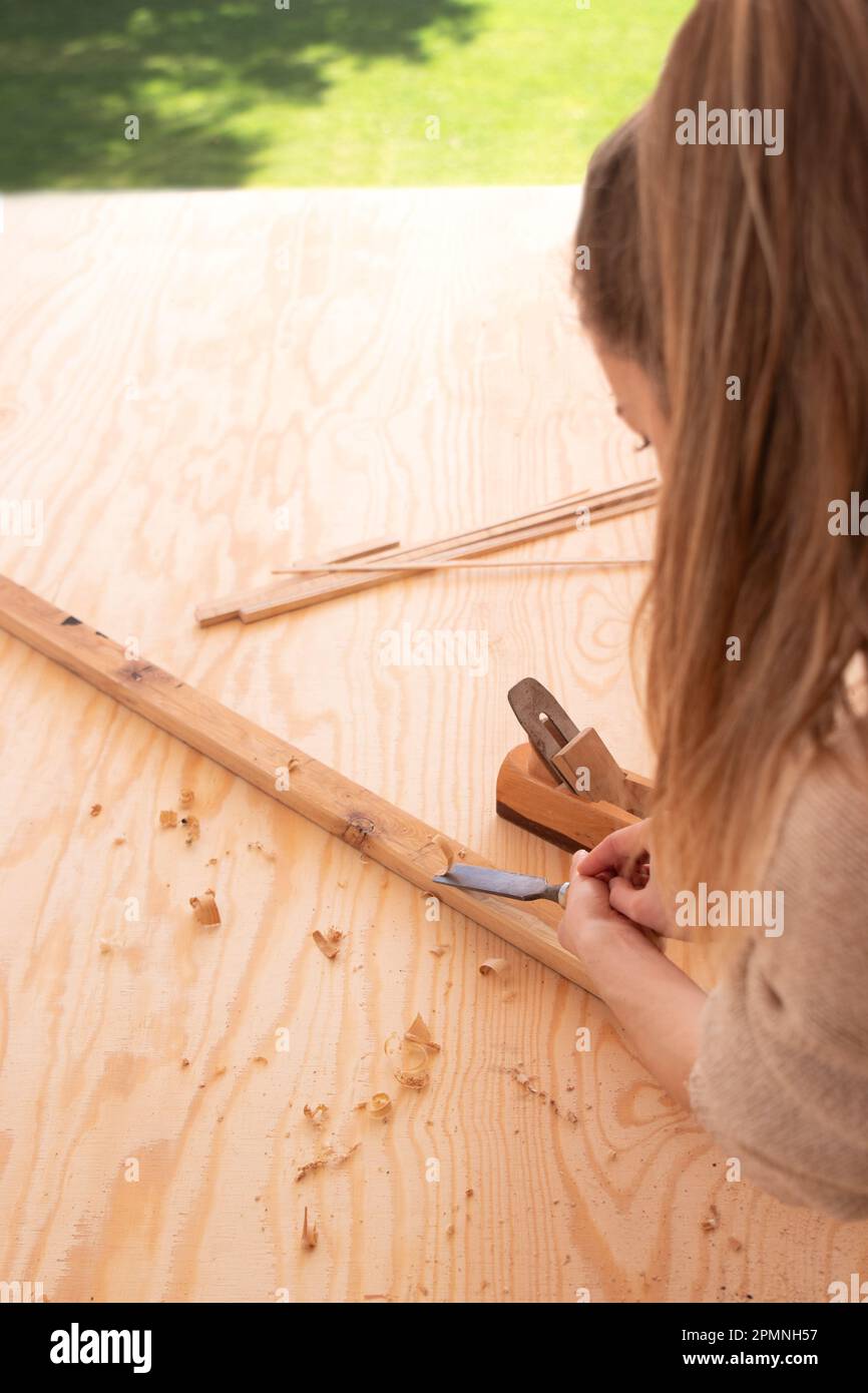 Craftswoman carving wood with chisel. Concentrated female joiner in ...
