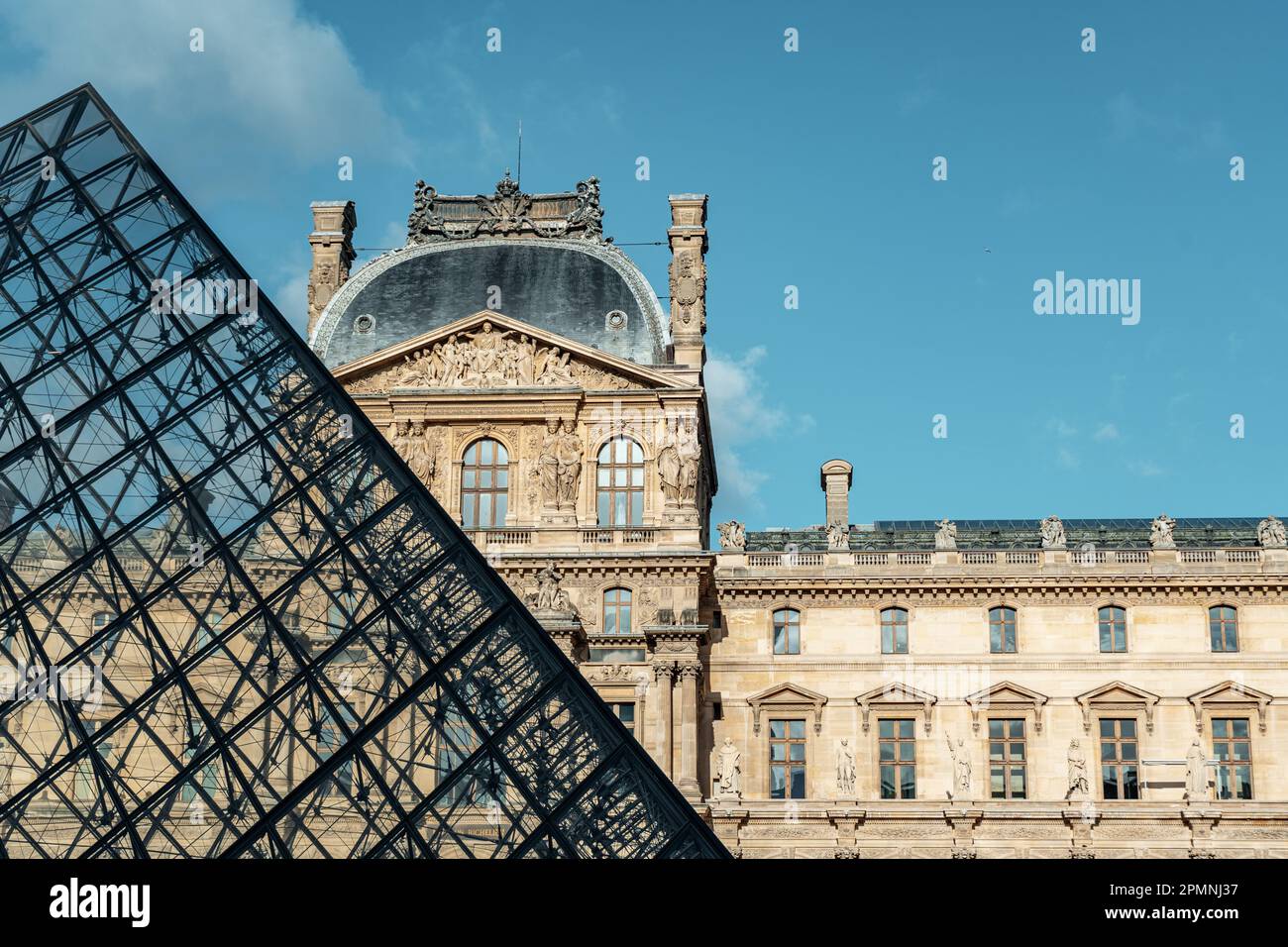 A low angle shot of the Louvre under a blue sky and sunlight in Paris ...