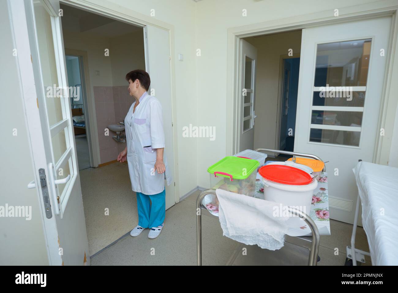 Nurse in a lab coats pulling a tray trolley with food in pots for ...