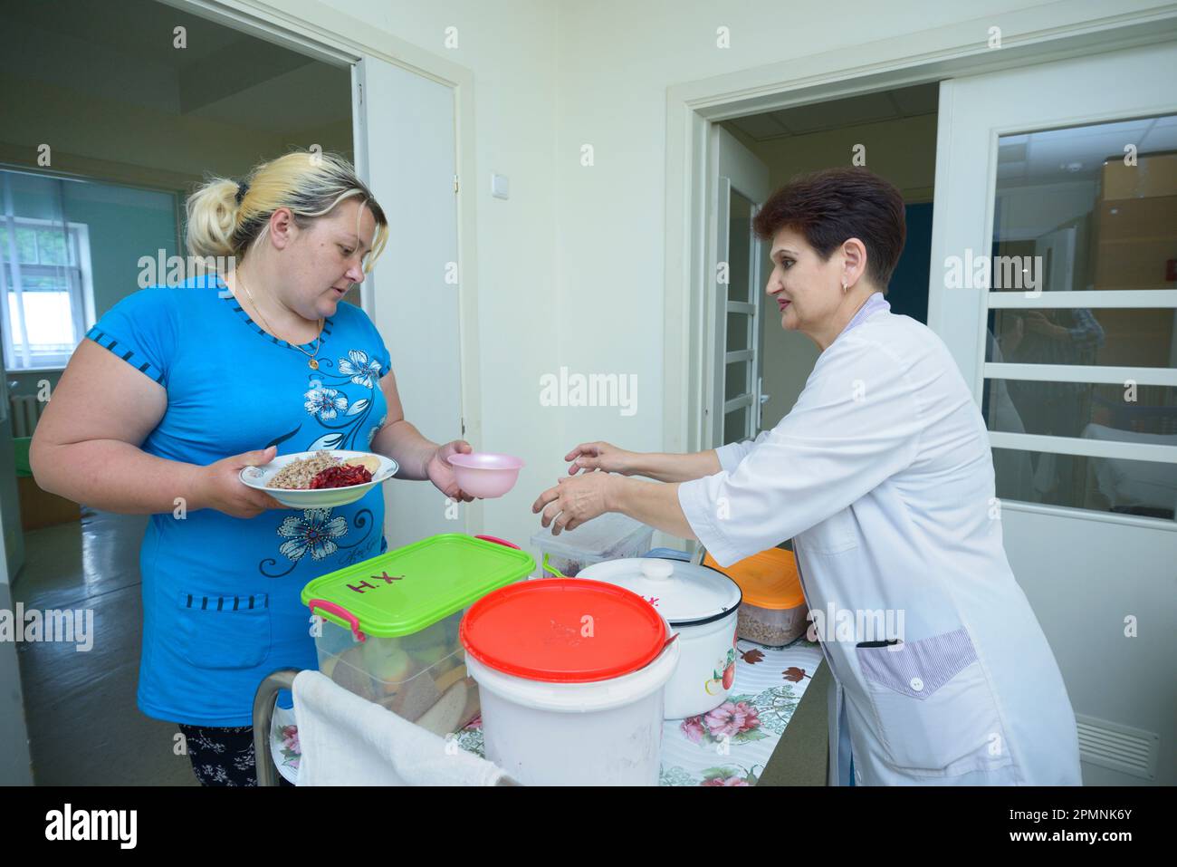 Nurse in a lab coats giving a patients plates with food from a tray ...