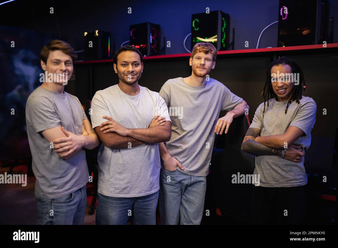 Positive multiethnic team of gamers looking at camera in cyber club ...