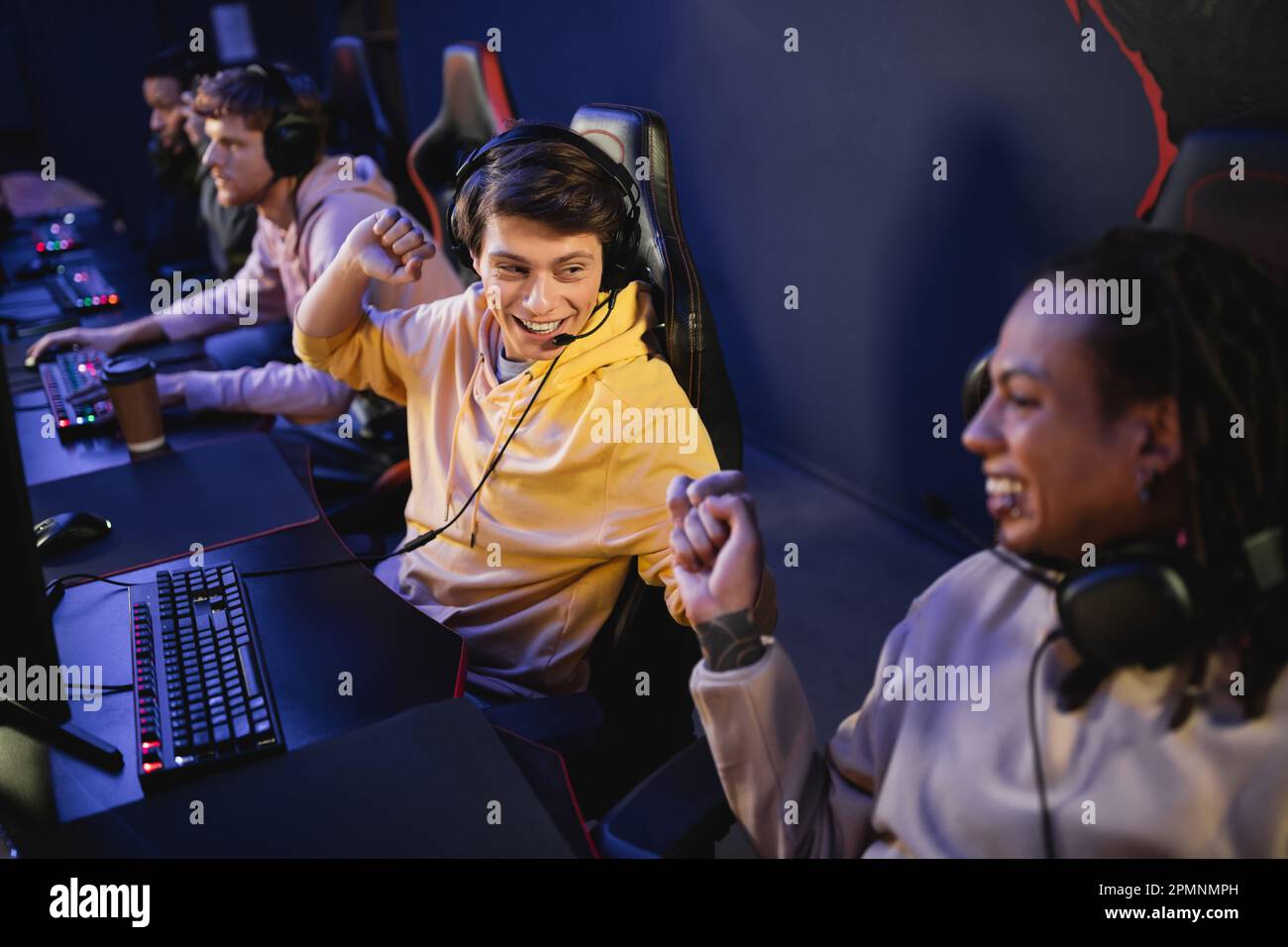 Cheerful man in headphones doing fist bump with multiracial friend in ...