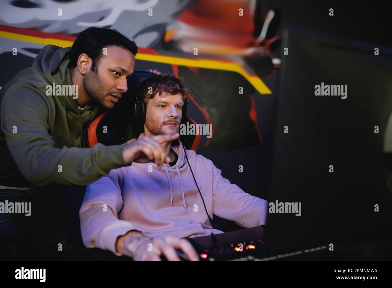 Indian man talking and pointing at computer monitor while friend ...