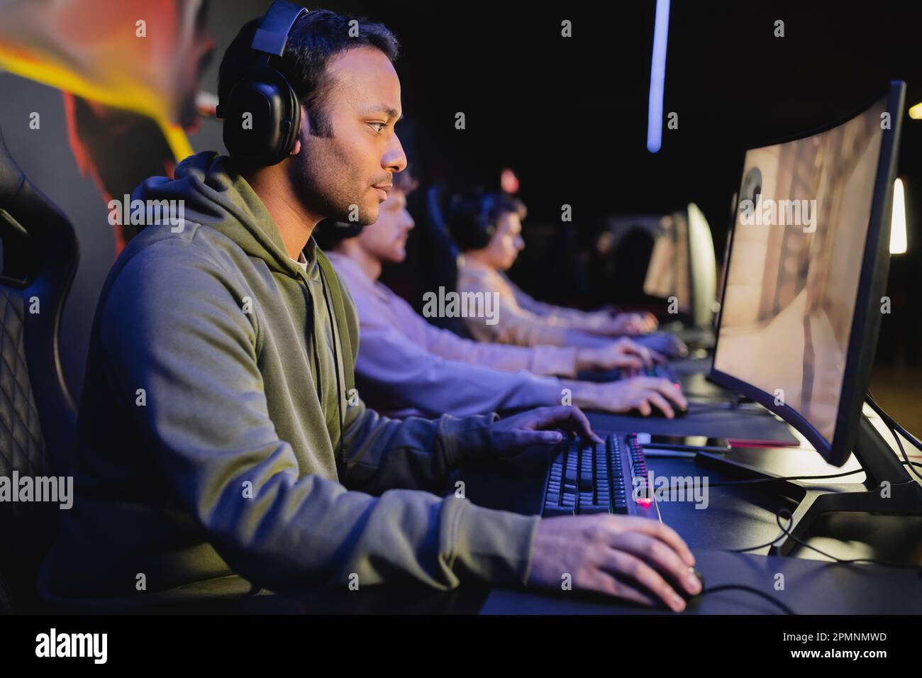 Side view of indian gamer in headphones playing video game with blurred ...