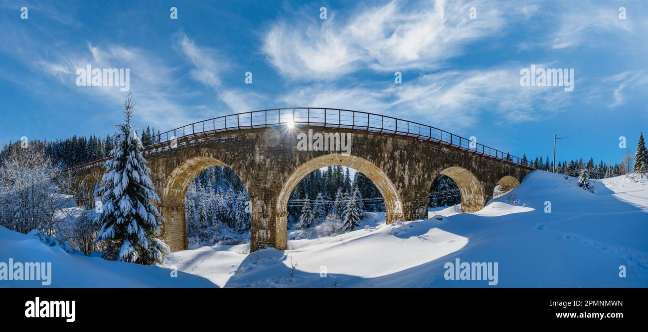 Stone viaduct (arch bridge) on railway through mountain snowy fir ...