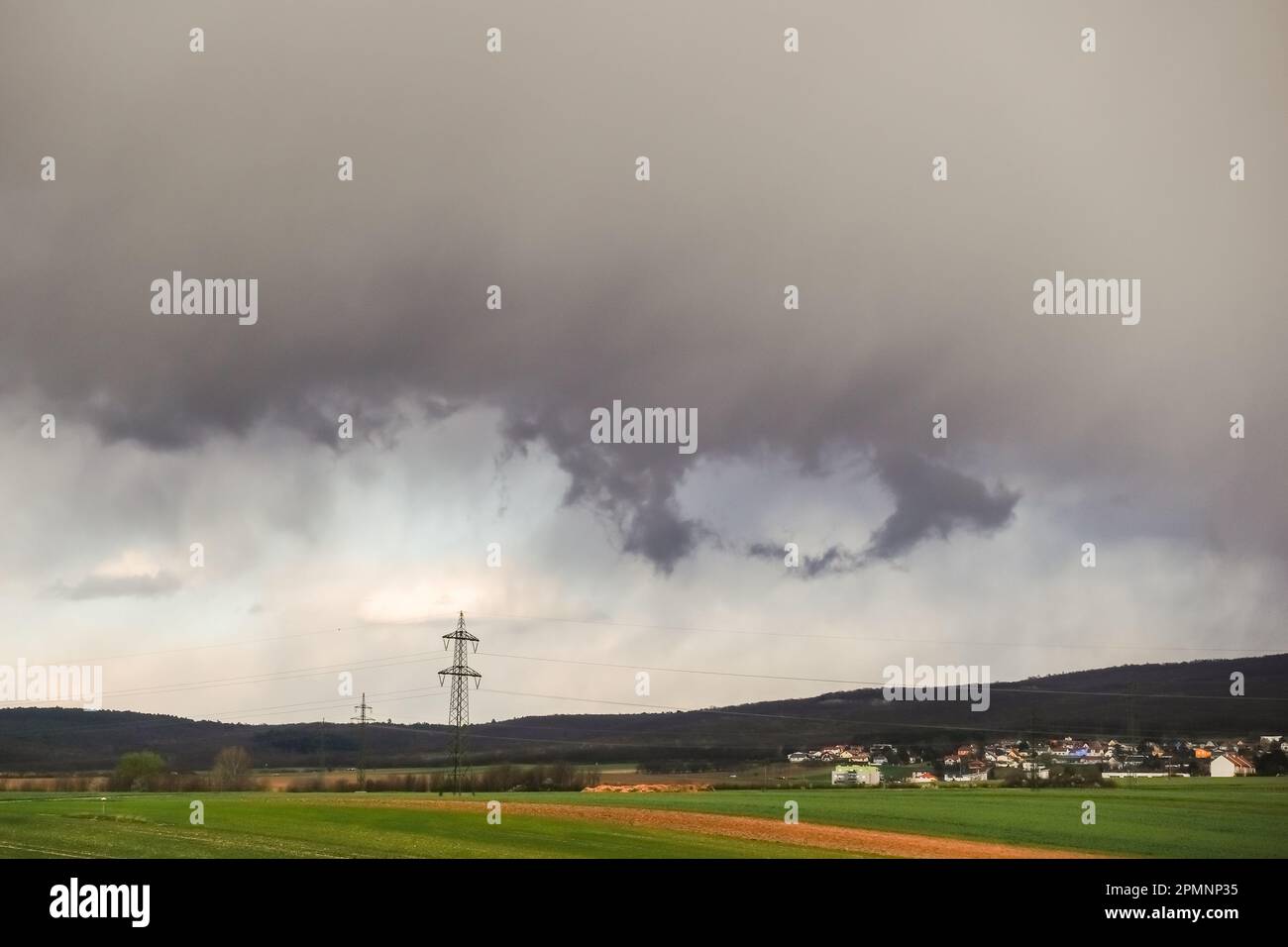 heavy gray rain clouds over a nature landscape with forest houses and ...