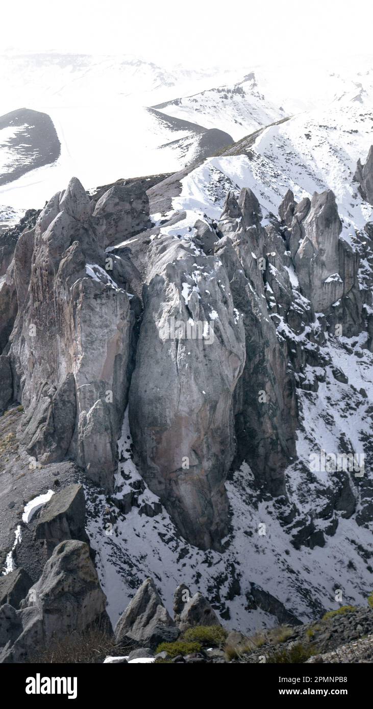 A vertical photograph of a majestic snow-capped mountain, taken from a ...