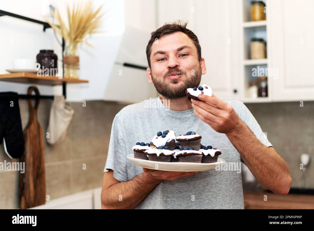 Happy man eating homemade cupcakes and smiling Stock Photo - Alamy