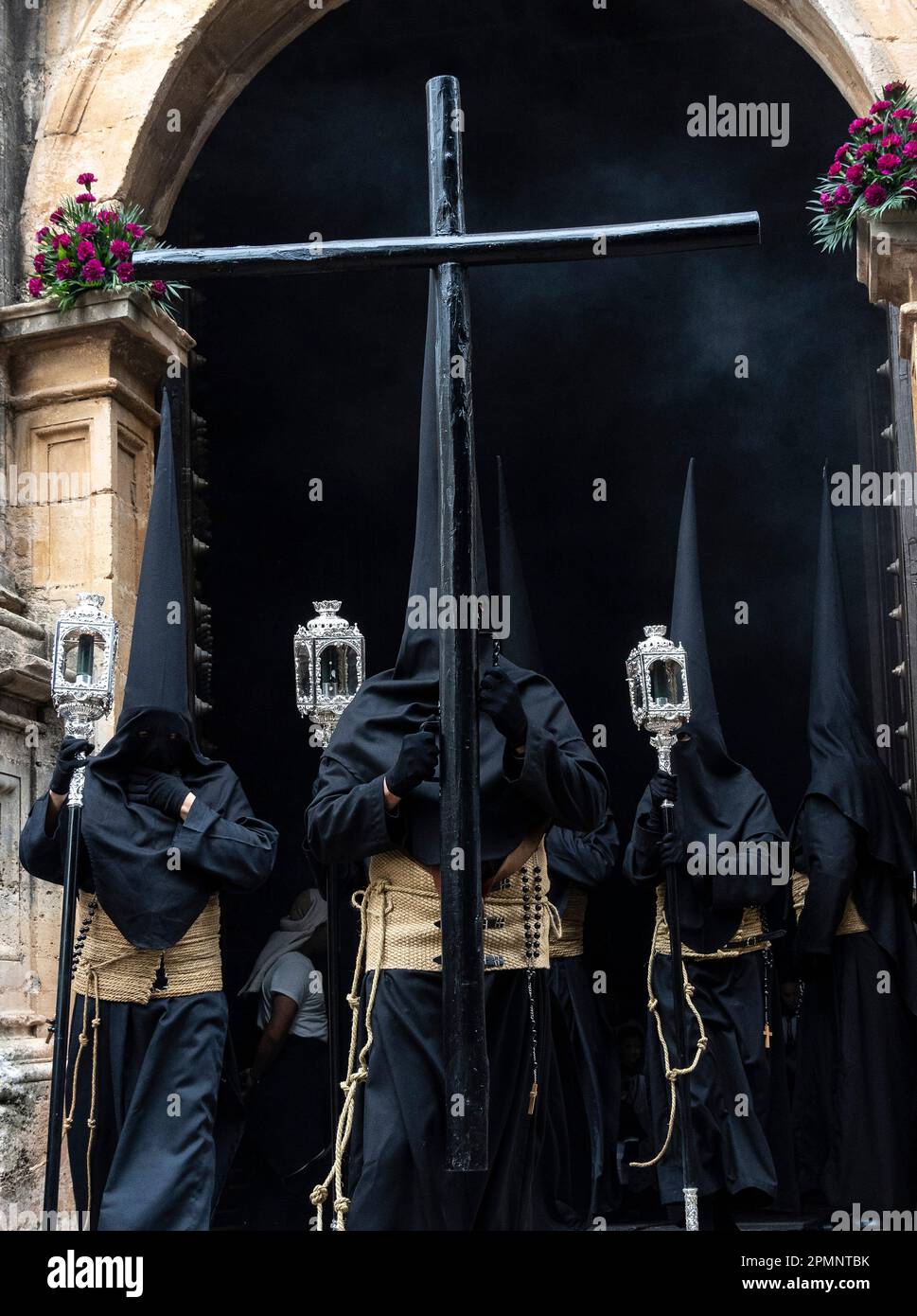 Penitents wearing black cone shaped hoods carry wooden crosses from the ...