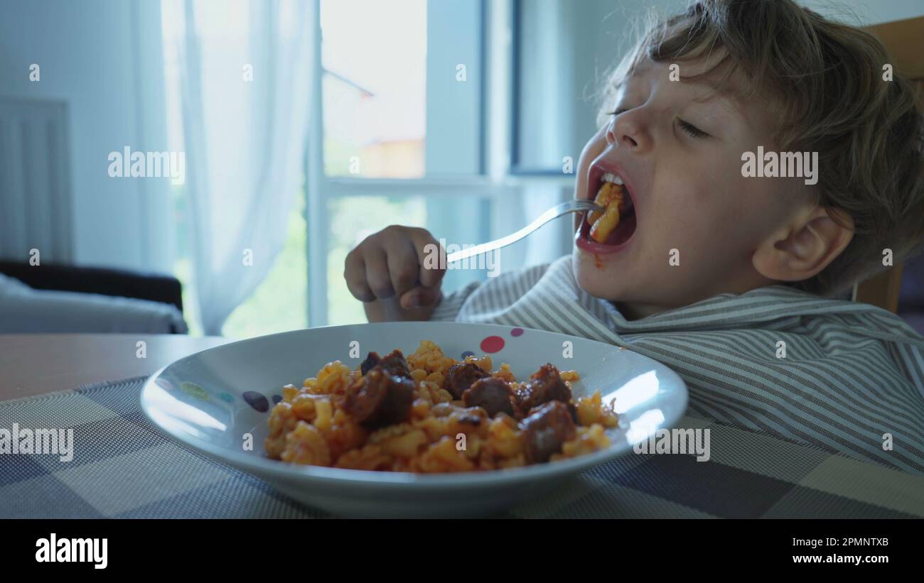 Child eating hot food burning mouth. One small boy spitting pasta out ...
