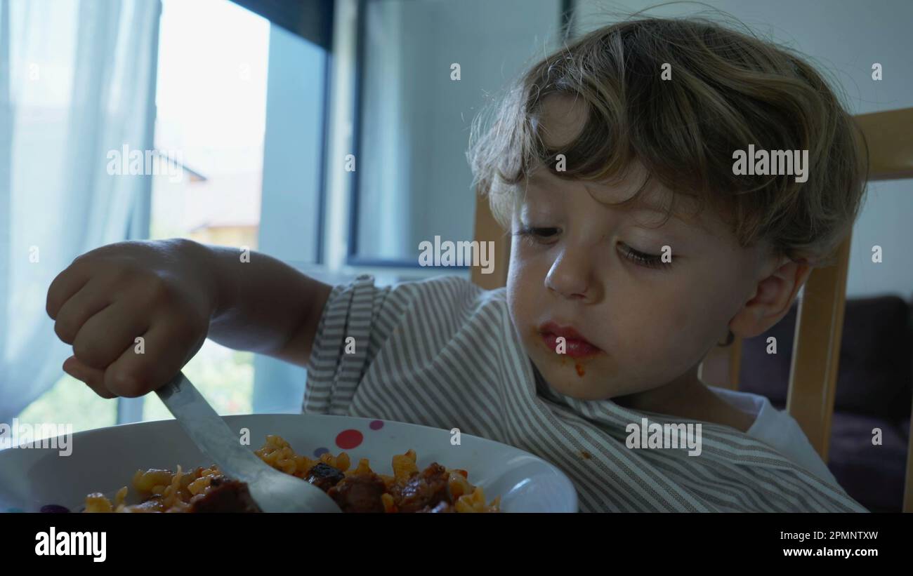 Child eating pasta food for lunch at home. Authentic lifestyle scene of ...