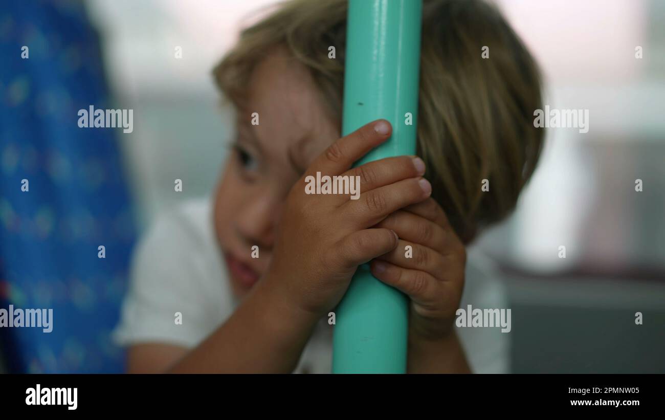Child leaning on metal bar inside tram city transportation. One small ...