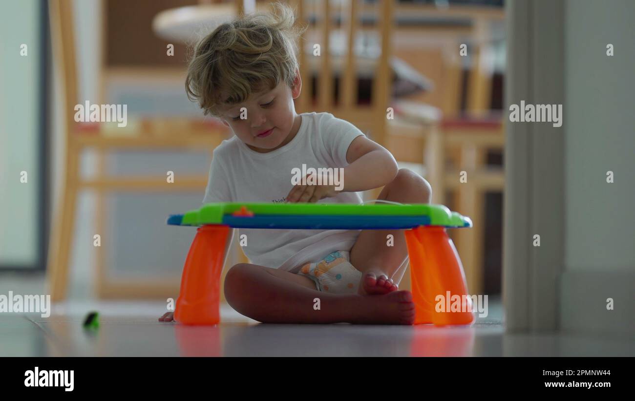 Little boy plays with magnetic erasable board at home floor. Childhood ...