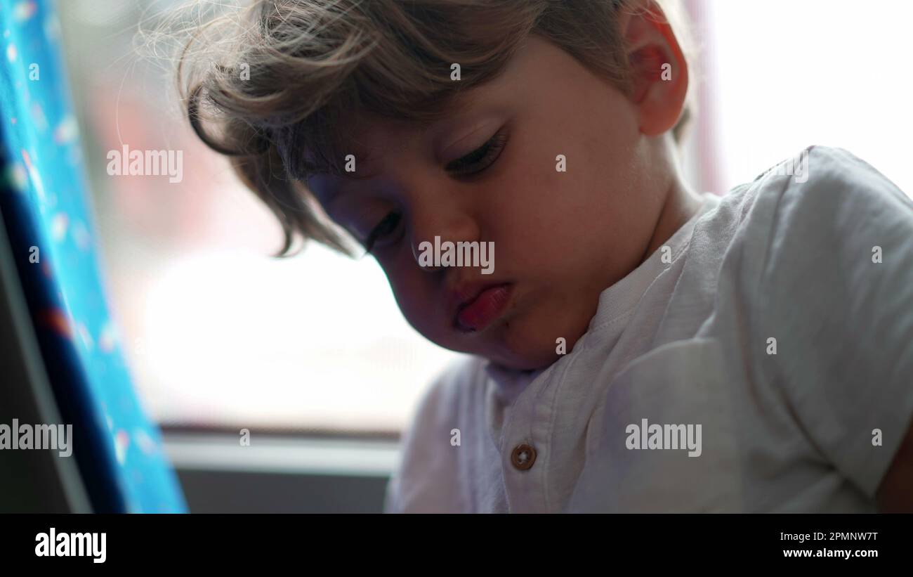 One bored little boy inside moving bus feeling upset. Angry kid closeup face with serious ...