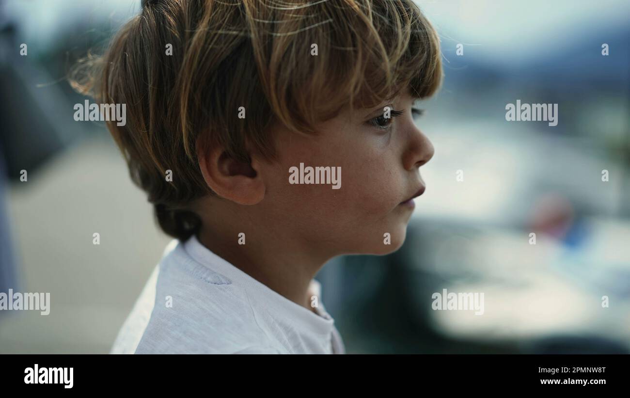 One thoughtful little boy staring at horizon with pensive expression ...