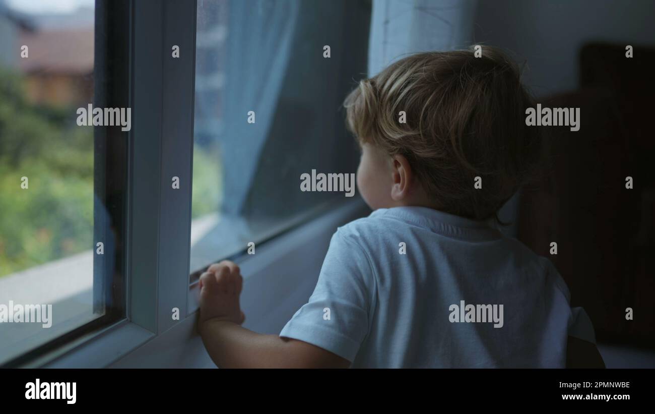 One little boy looking out window at home. Child staring out from the ...