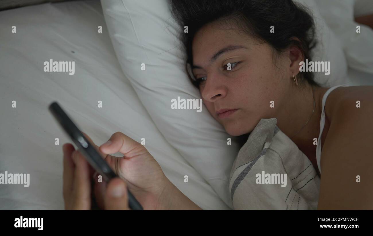 Woman using phone laid in bed. Female person looking at smartphone ...