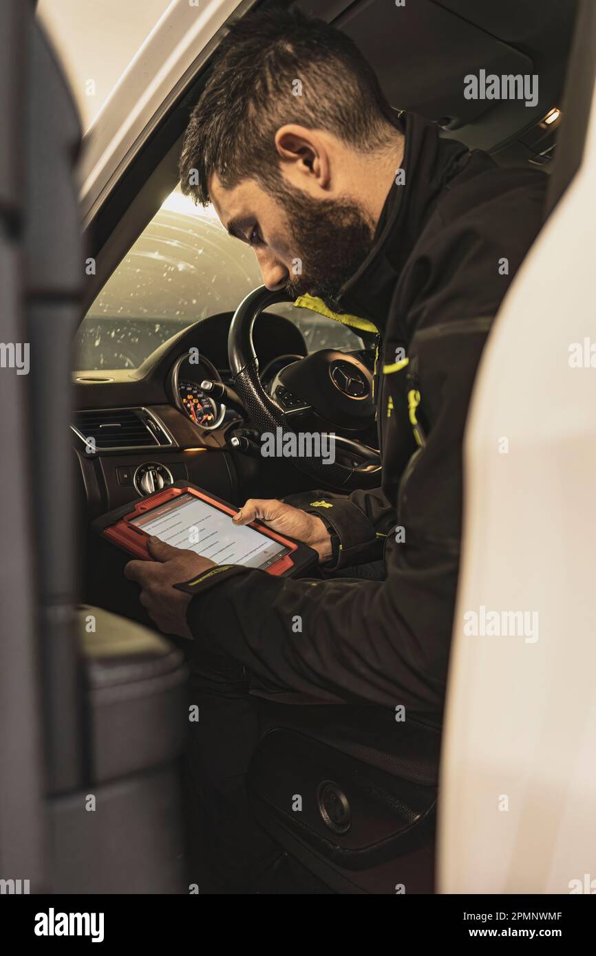 Milan, Italy 11 april 2023: A mechanic's hands use a diagnostic tool to ...