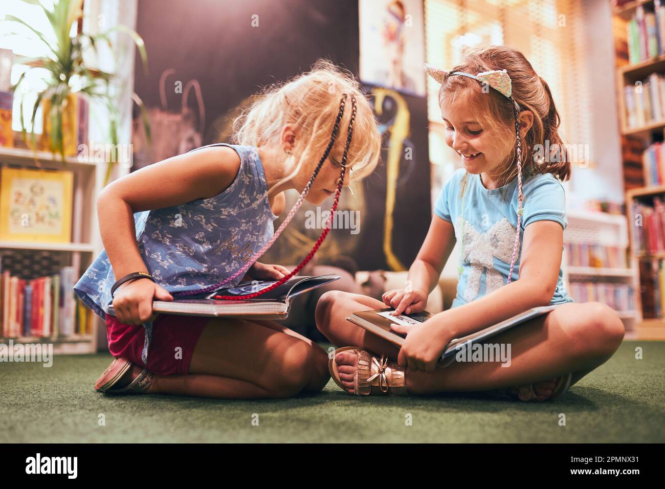 Two primary schoolgirls doing homework in school library. Students ...