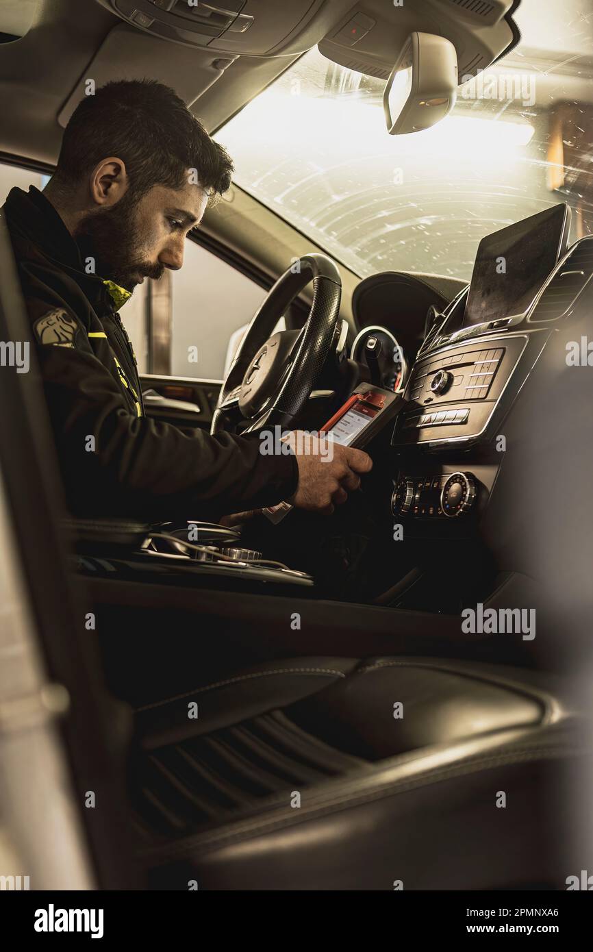 Milan, Italy 11 april 2023: A mechanic's hands use a diagnostic tool to ...